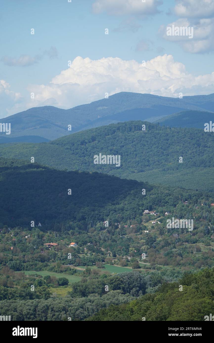 A scenic landscape with a rolling hill, with houses in the distance in ...