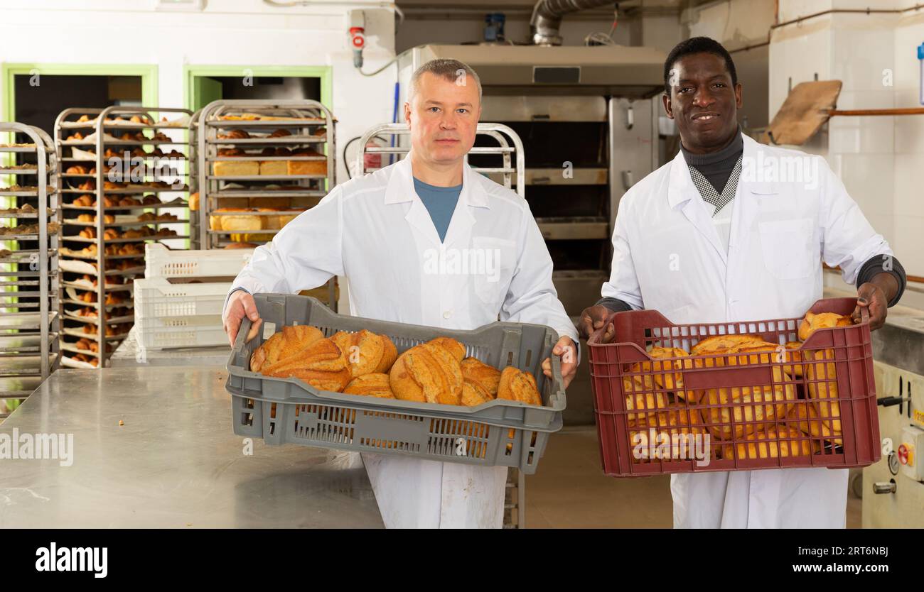 Portrait of two man bakery employees offering delicious bread in bakery ...