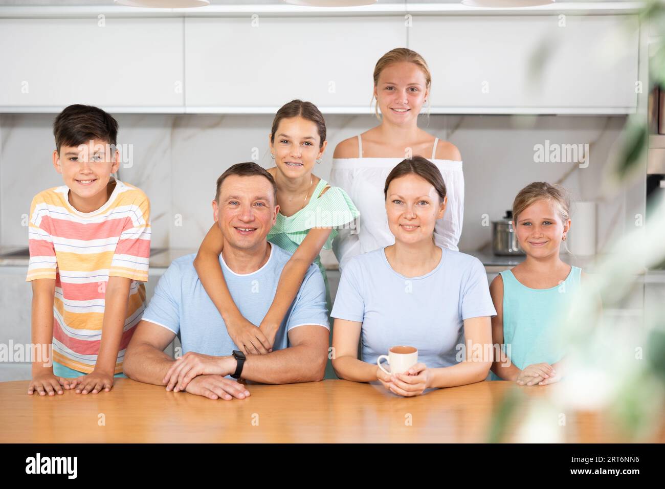Happy dad and mum with three daughters and son is standing near kitchen ...