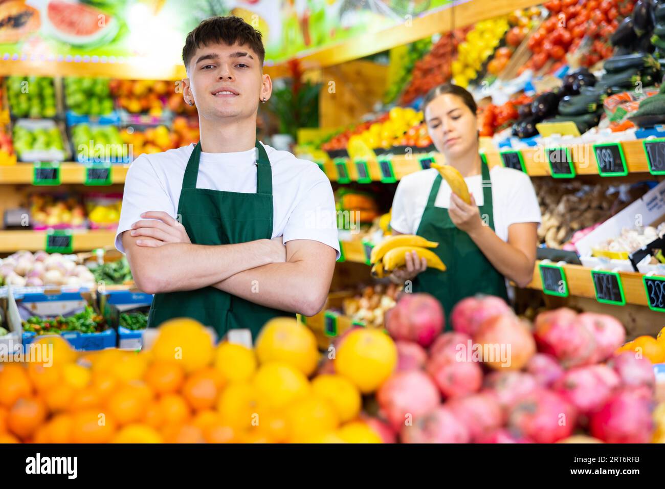 Portrait of positive young salesman in the vegetable section of grocery ...