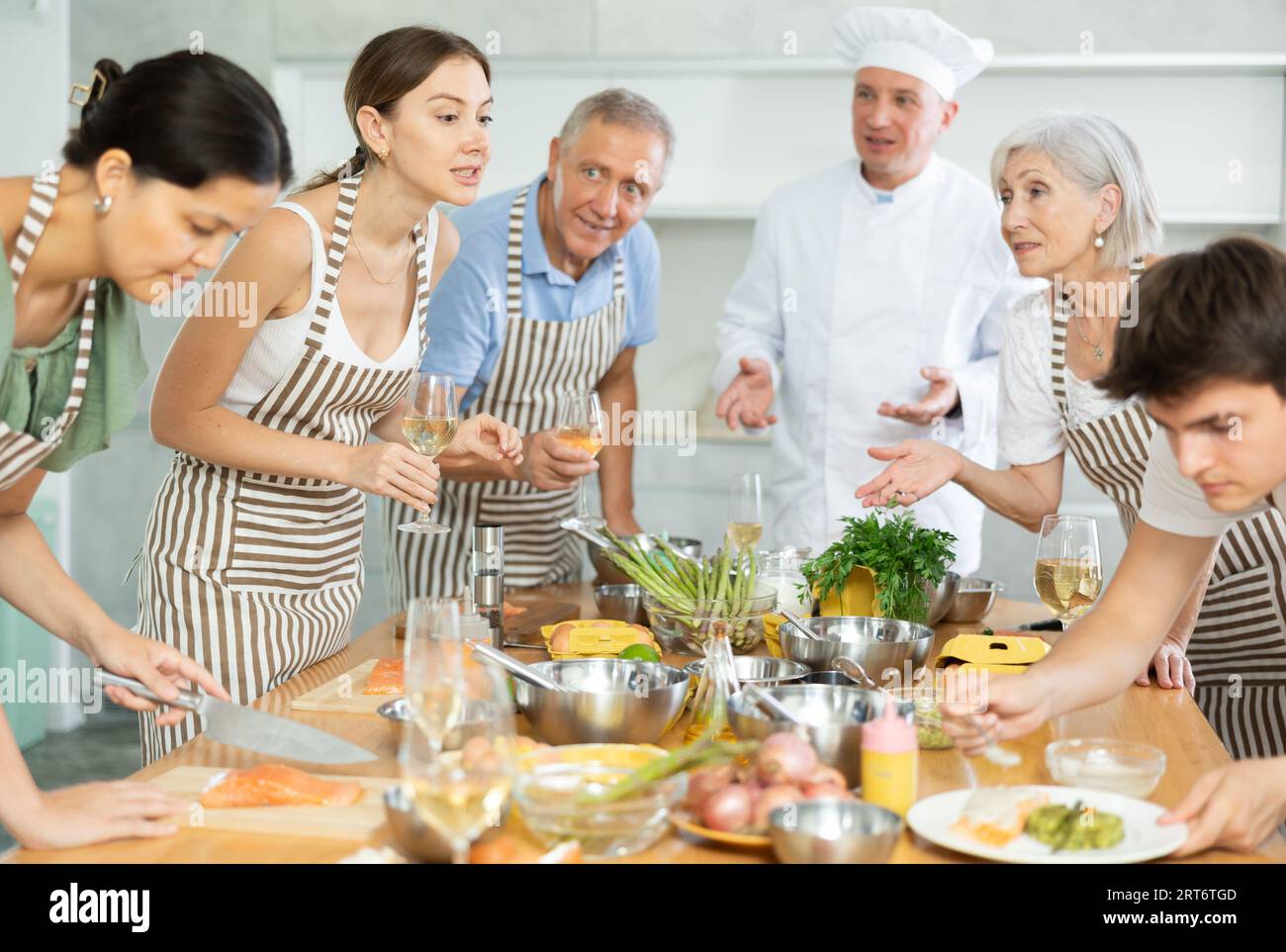 Chef in uniform teaches cooking class students how to clean and cut ...