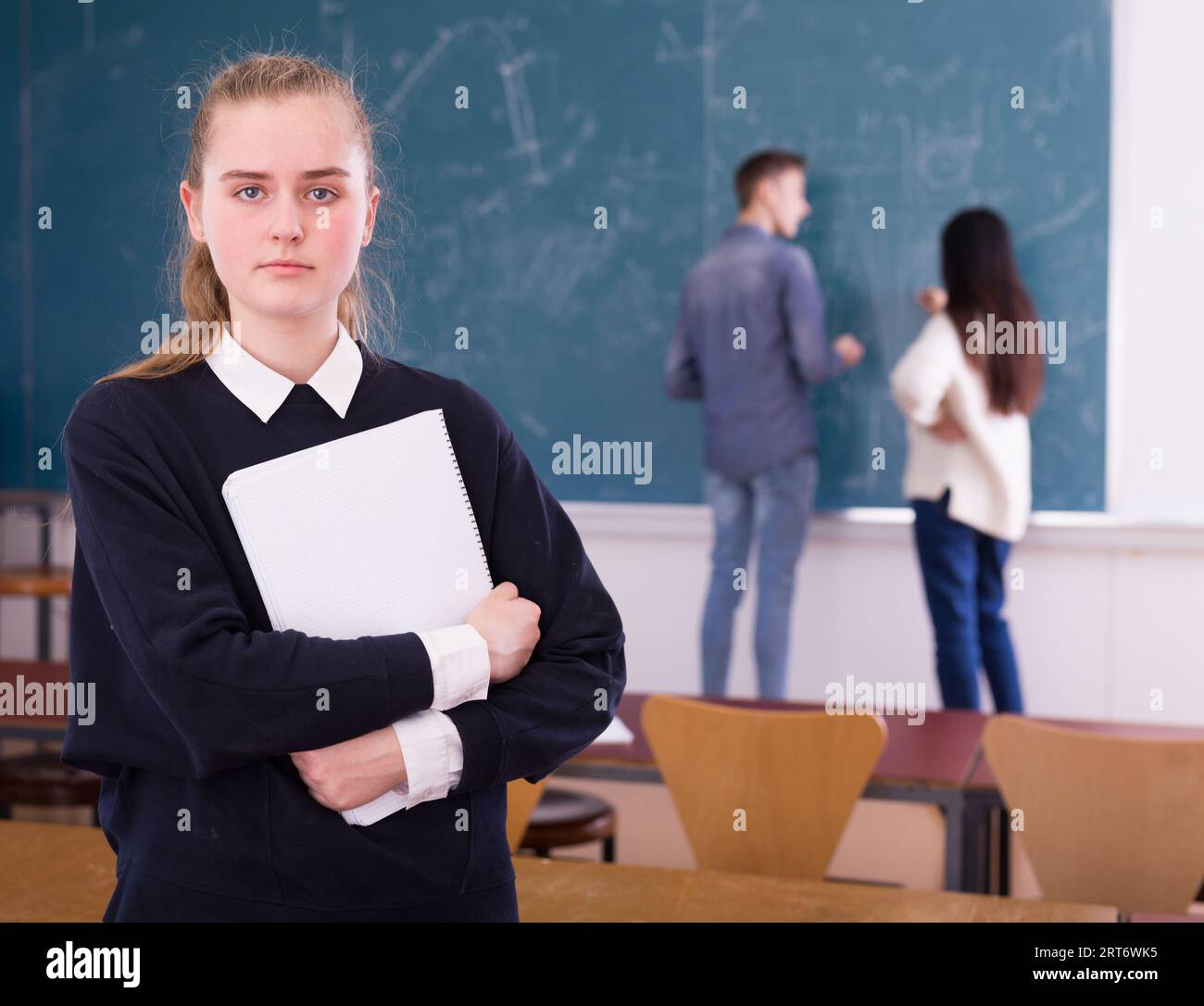 Confident teenage girl with workbooks in classroom Stock Photo - Alamy