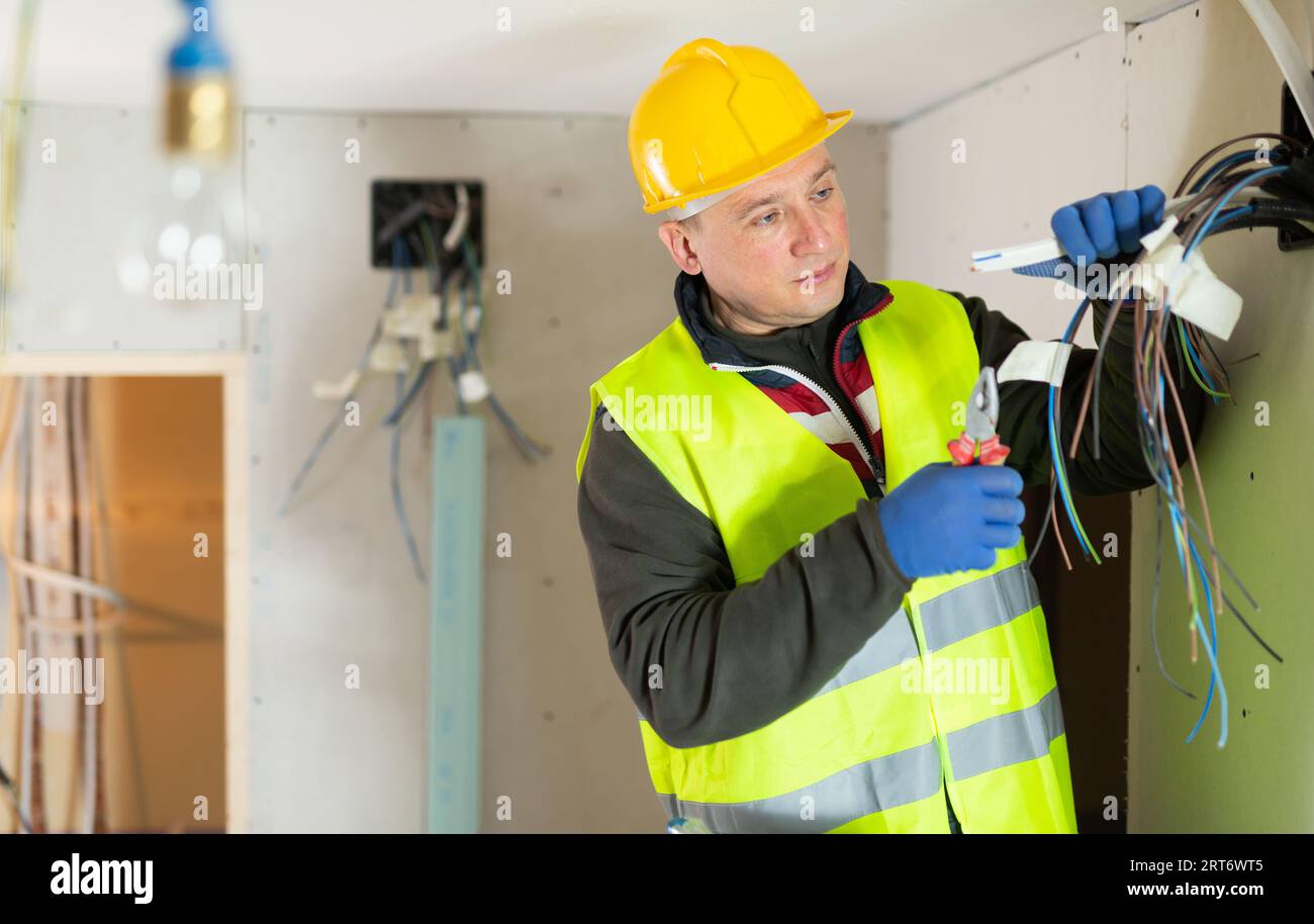 Worker repairing wires while installing electricity Stock Photo - Alamy
