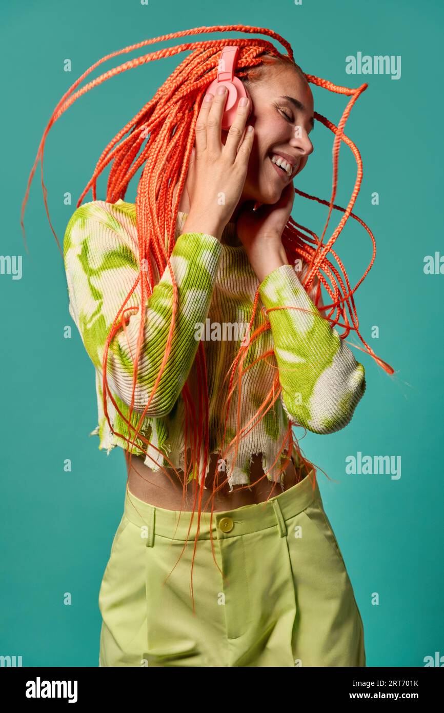 Young happy female in colorful outfit with orange Afro braids touching ...