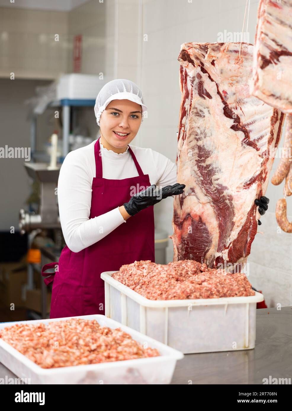 Happy female butcher showing big piece of beef ribs in meat section of ...