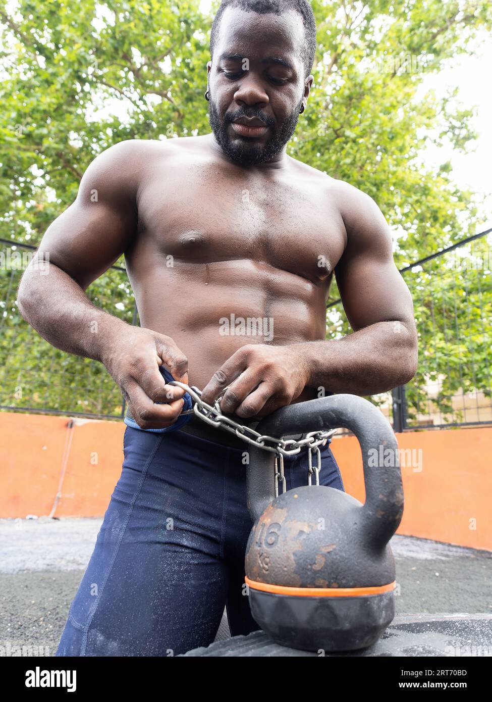From below of black male athlete in sportswear while kneeling on ground ...