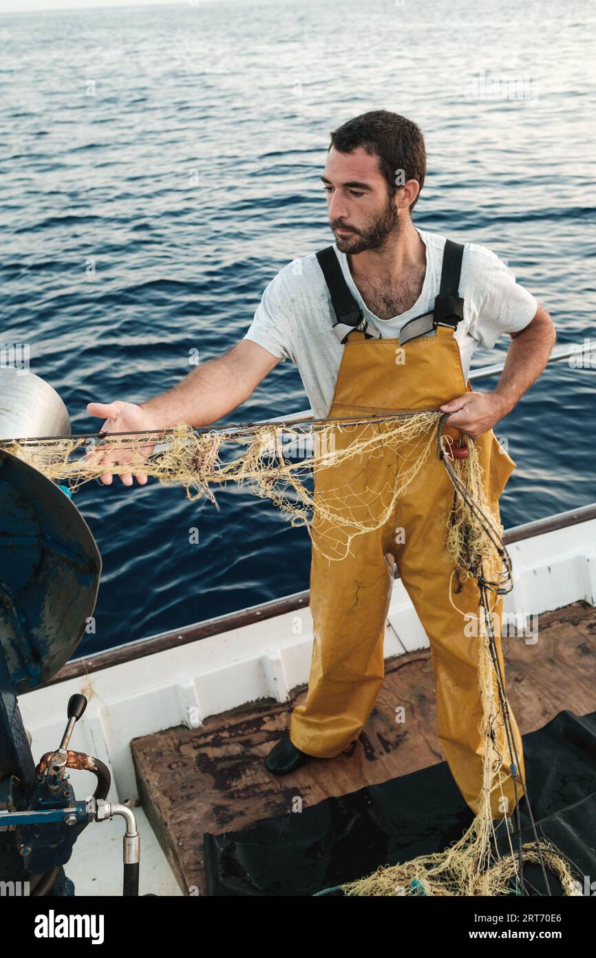 From above focused bearded male fisher in uniform seiner hunting fish ...