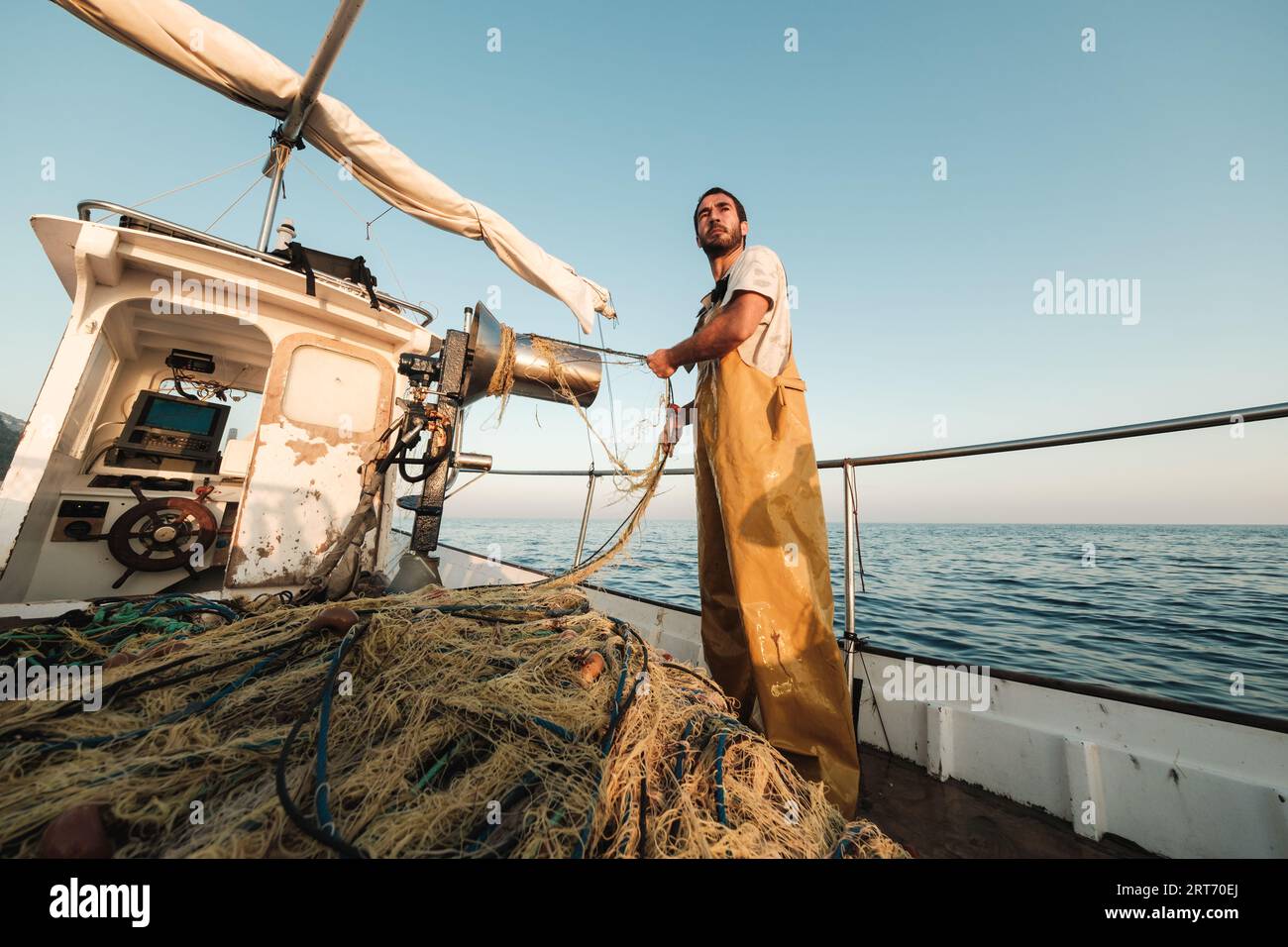 From below focused bearded male fisher in uniform seiner hunting fish ...