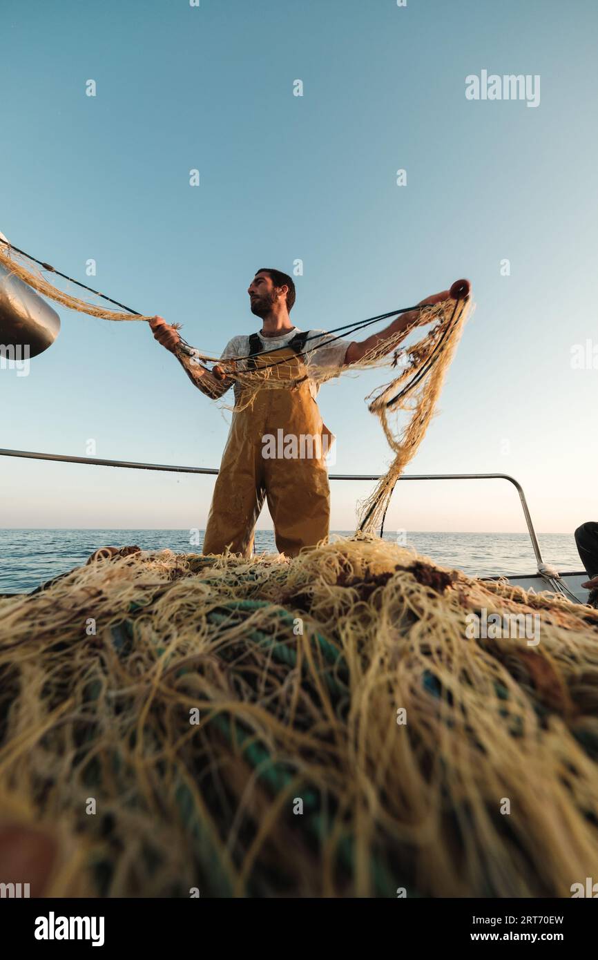 From below focused bearded male fisher in uniform seiner hunting fish ...