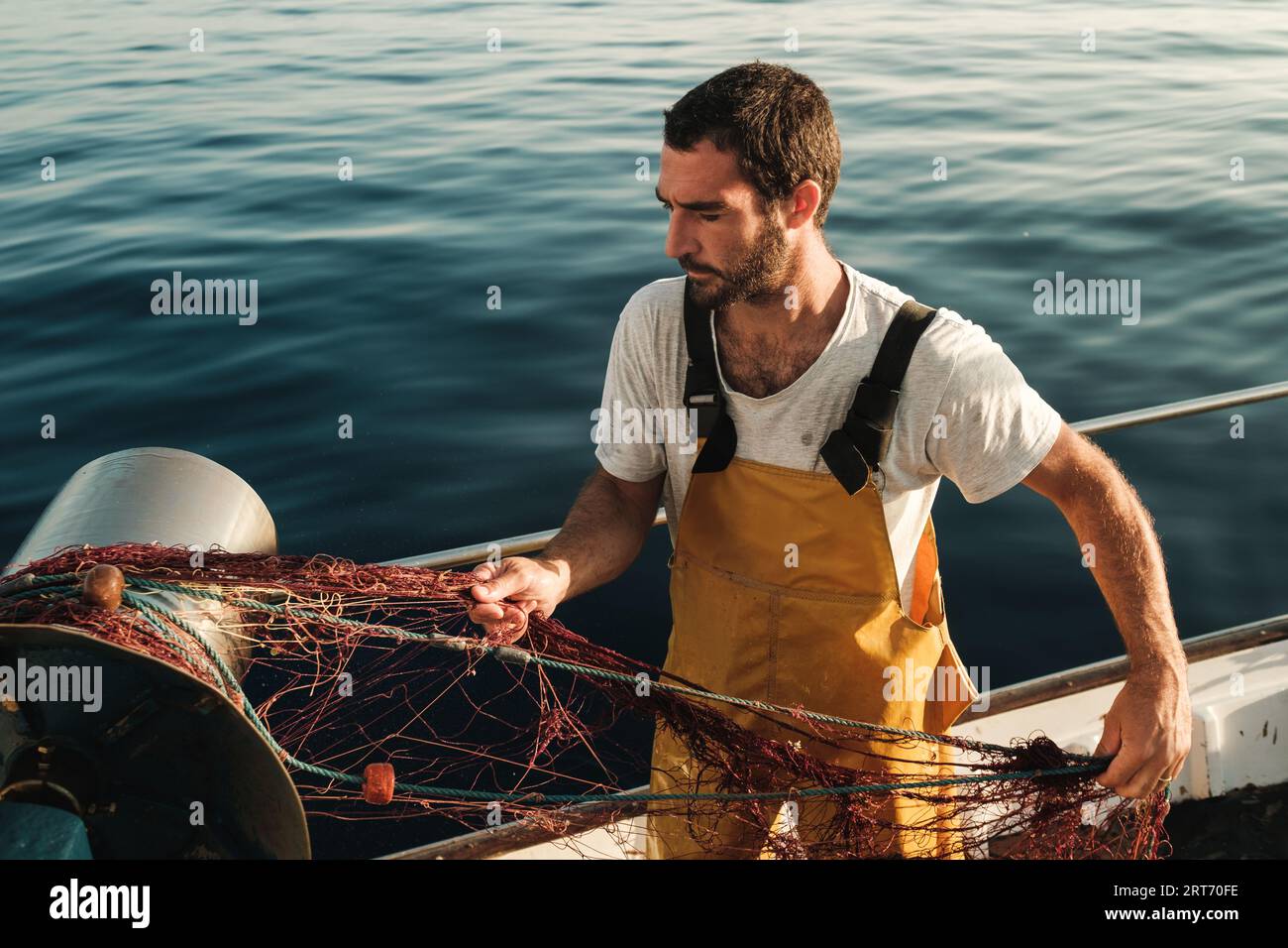 From above focused bearded male fisher in uniform seiner hunting fish ...