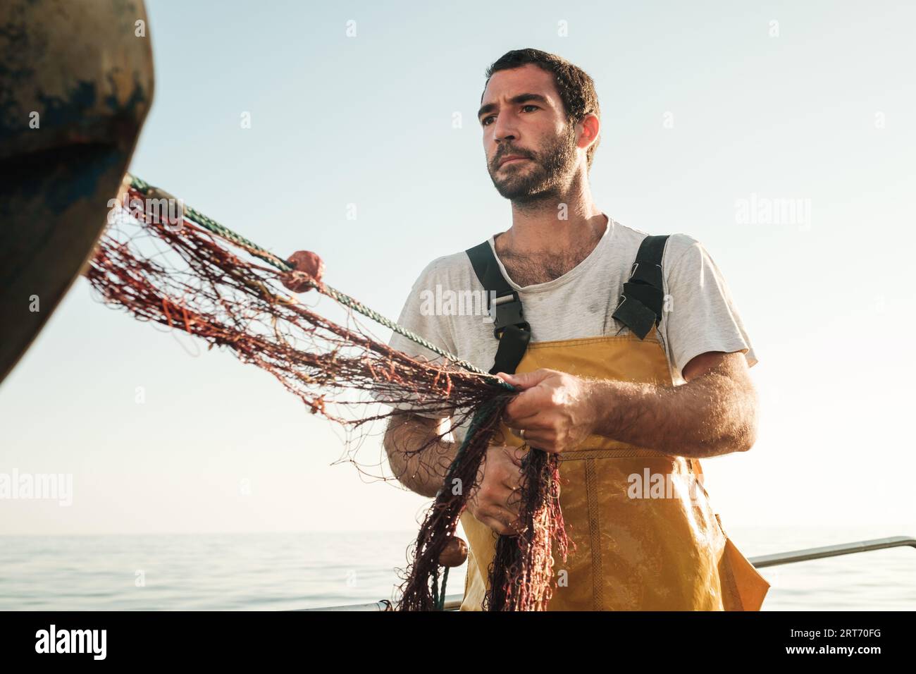 From below focused bearded male fisher in uniform seiner hunting fish ...