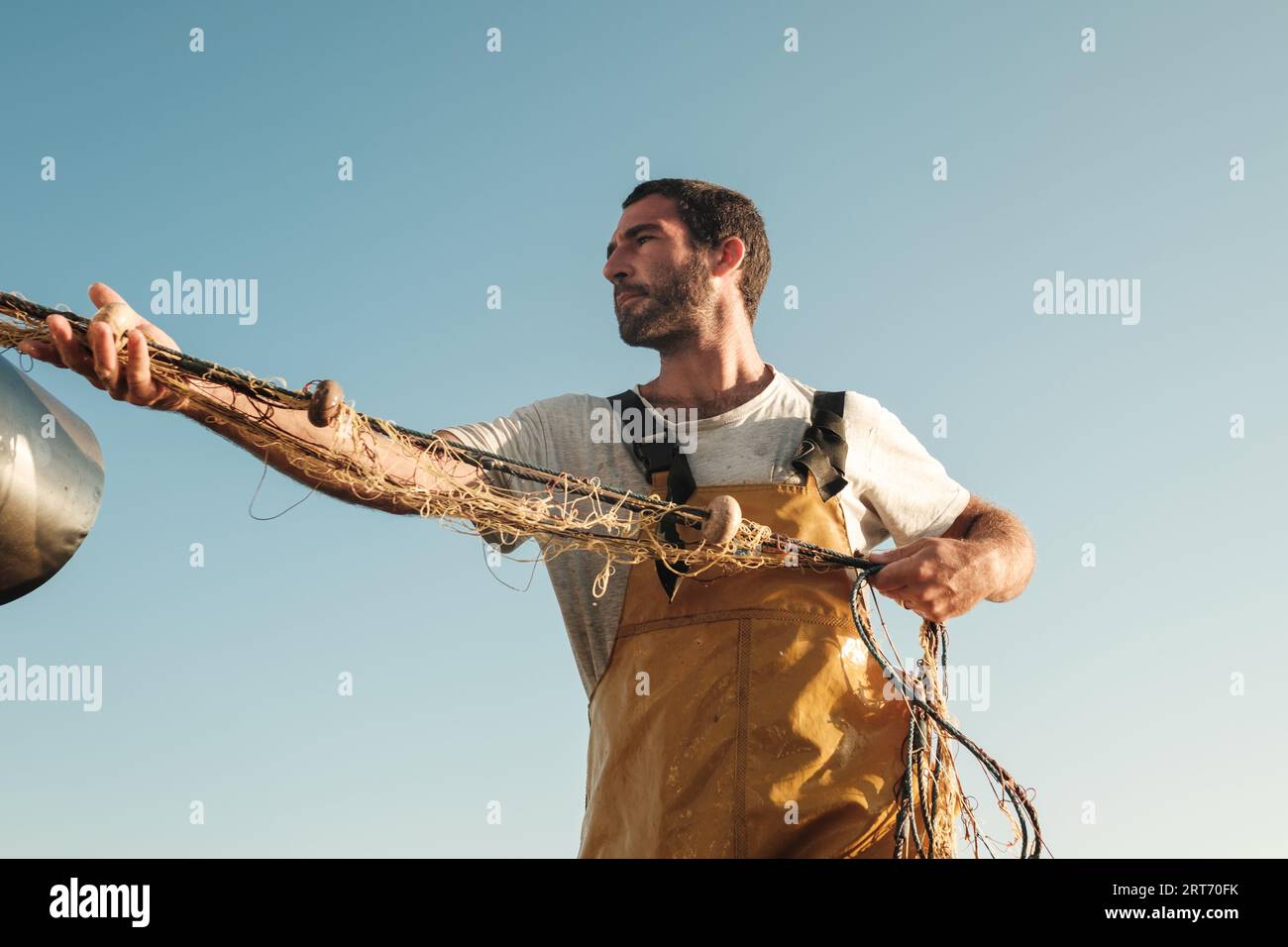 From below focused bearded male fisher in uniform seiner hunting fish ...