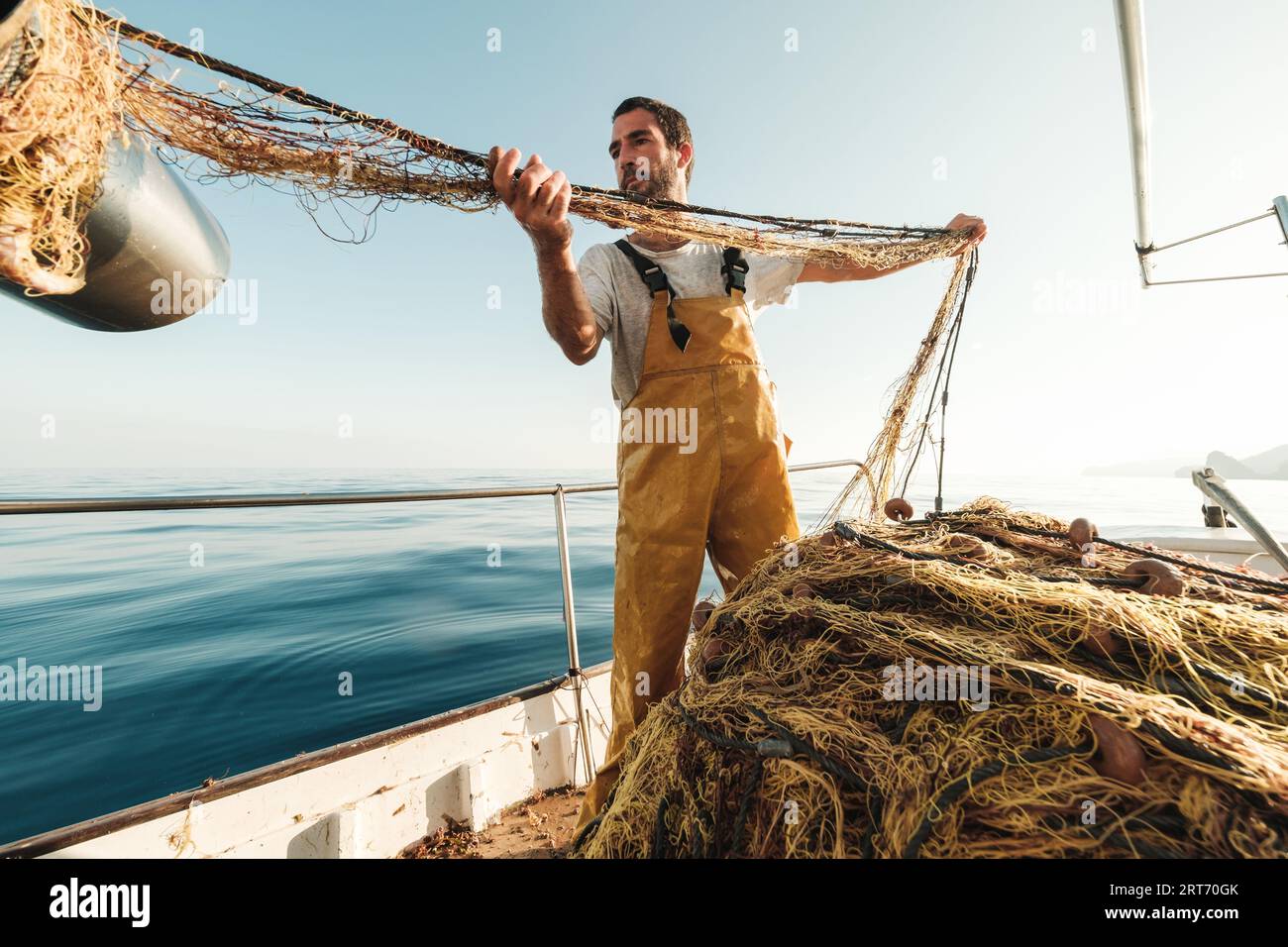 From below focused bearded male fisher in uniform seiner hunting fish ...