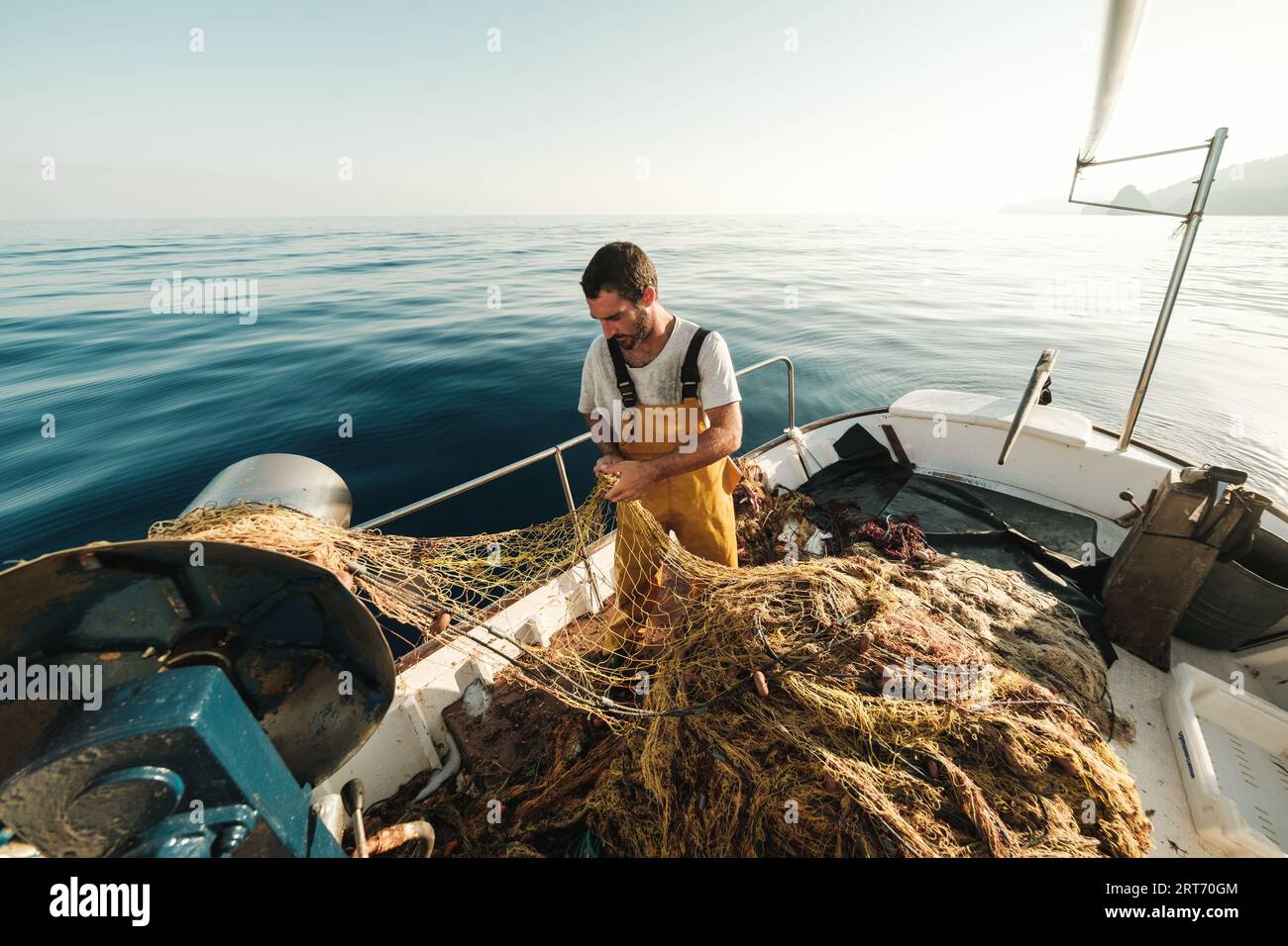 From above focused bearded male fisher in uniform seiner hunting fish ...