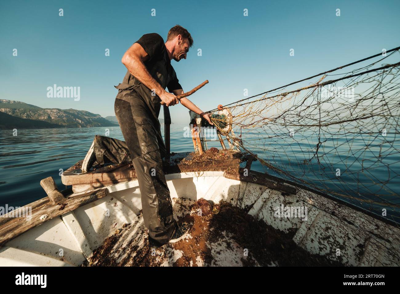 From below focused bearded male fisher in uniform seiner hunting fish ...