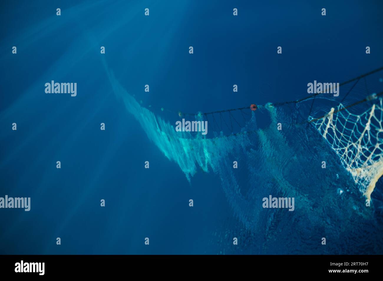Large net with ropes floating in deep blue sea water under sunlight ...