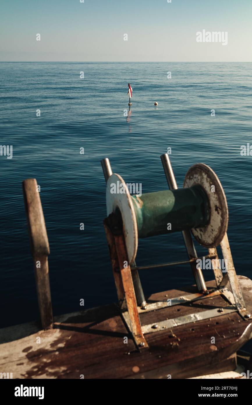 Metal rusty coil for traditional fishing placed near blue rippling sea ...