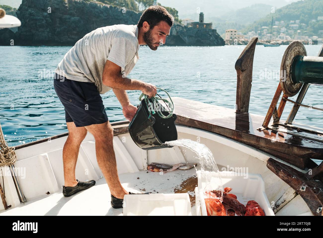 Full body of serious Hispanic male pouring water from bucket on fish in ...