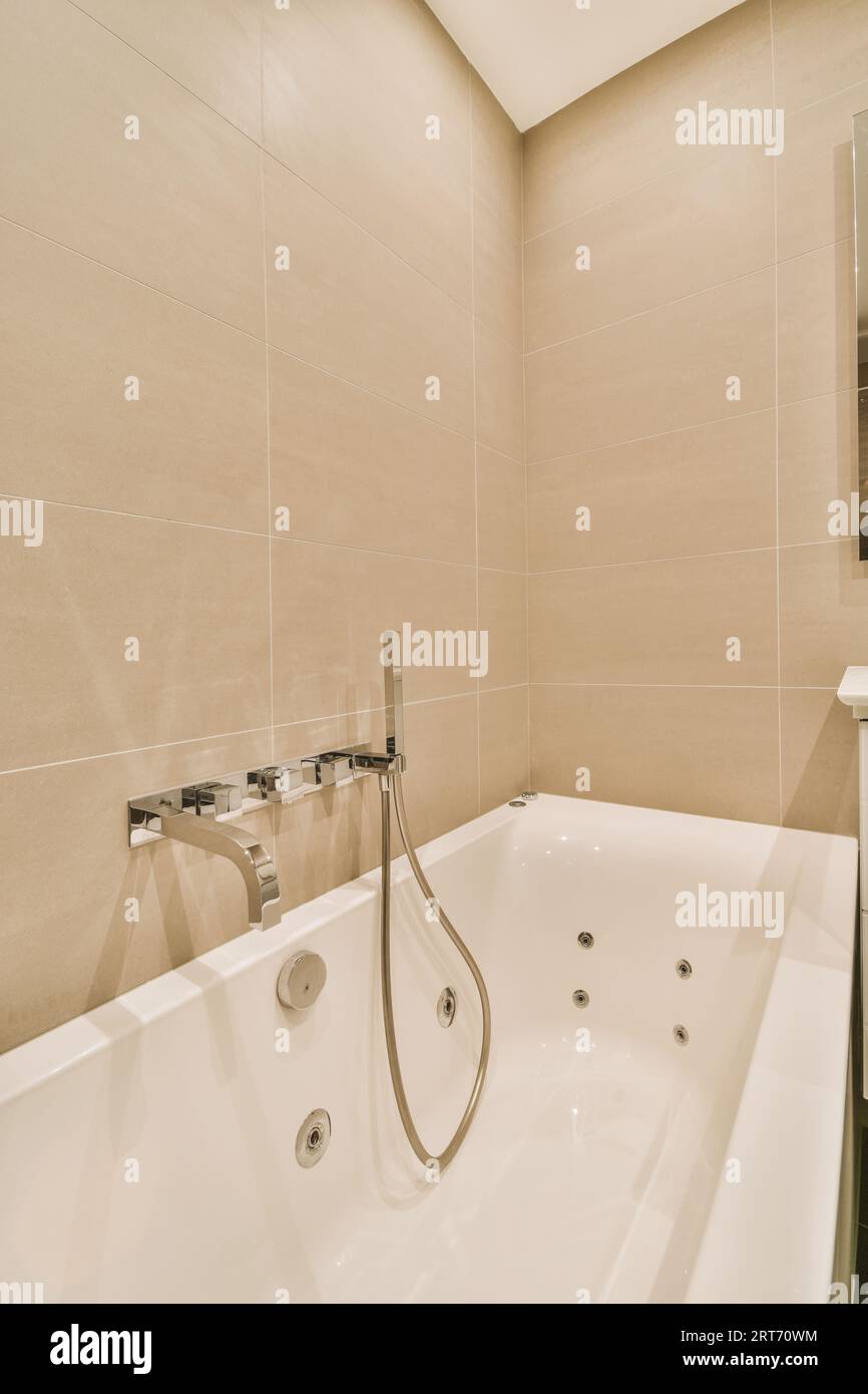 Interior design of bathtub surrounded by tiled walls with modern ...