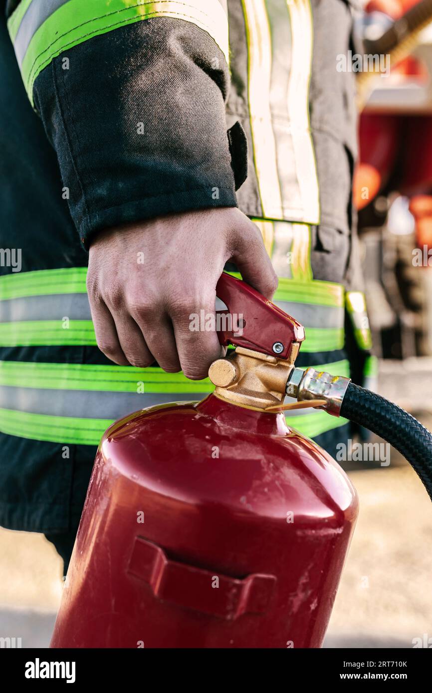 Crop anonymous firefighter wearing protective uniform while carrying ...