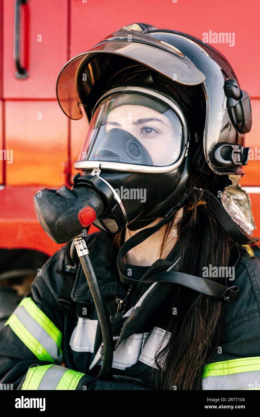 Female firefighter in professional uniform and protective respirator on ...