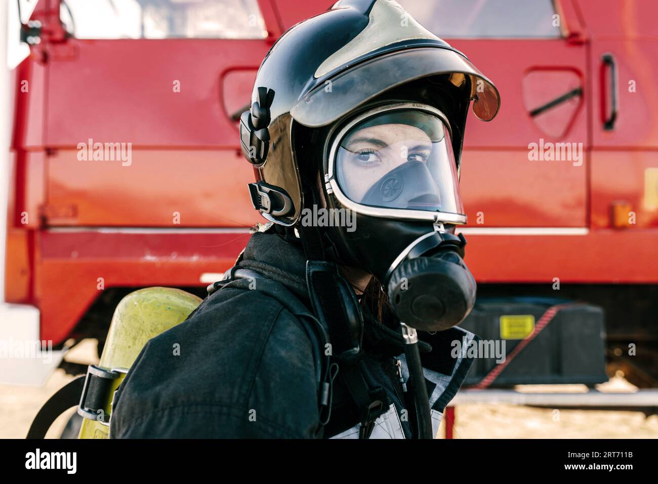 Side view of female firefighter in protective uniform and respirator ...
