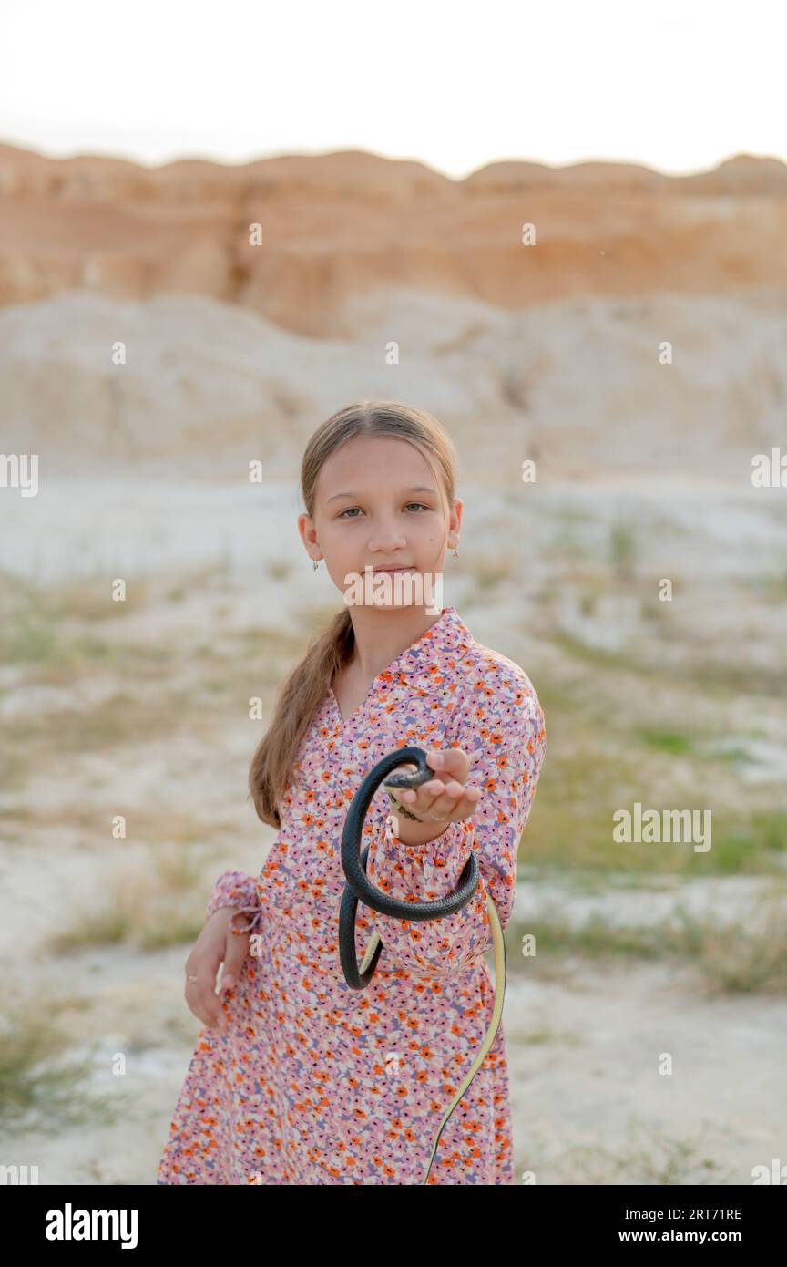 A teenage girl plays with a snake, holding it in her hands. Children ...