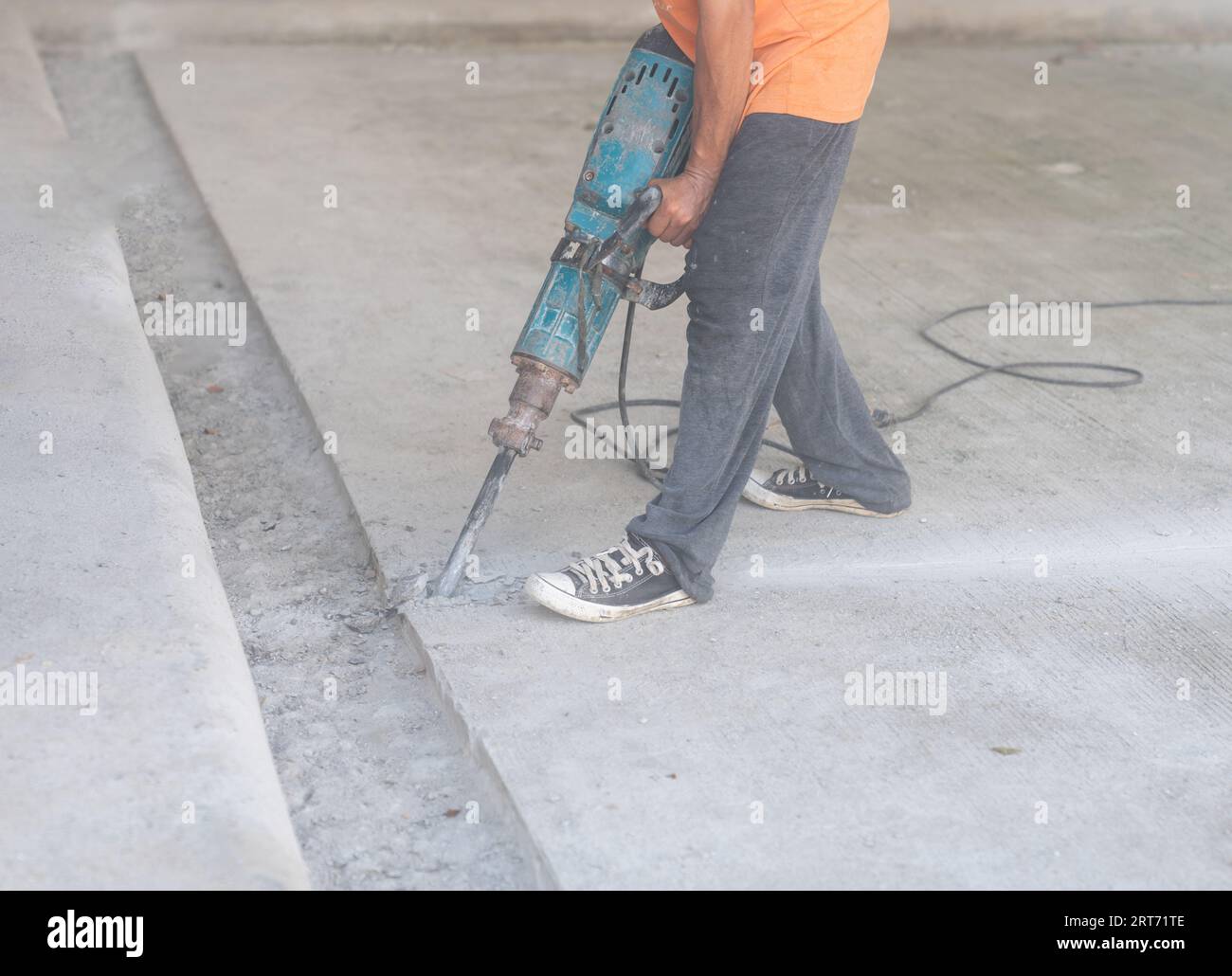 Worker at construction site demolishing concrete floor with electric ...