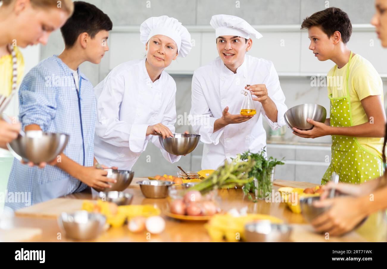 Man and woman cooks, during culinary master class, tell children rules ...