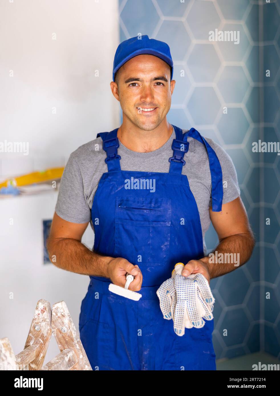 Professional man builder in blue construction overalls and cap posing ...