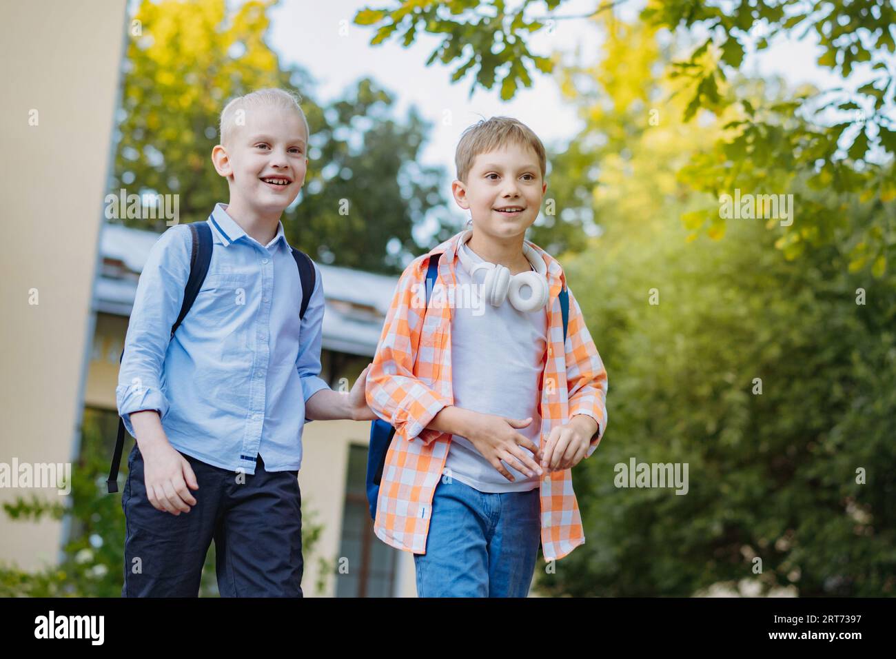 Happy caucasian children running from school with backpacks on sunny ...