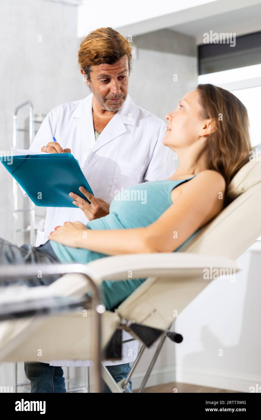 Friendly doctor talking to patient, assessing health status in clinic ...