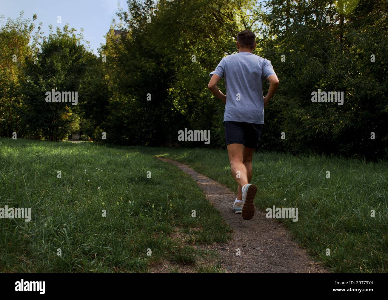 a man is jogging along the path in the park in summer, a healthy ...