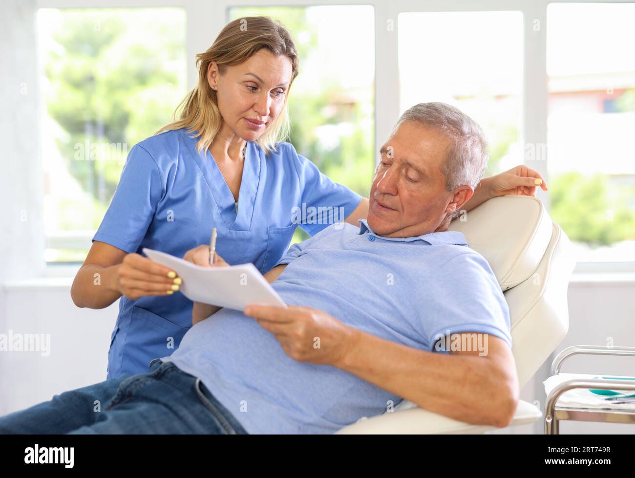 Elderly patient signing informed consent form during medical ...