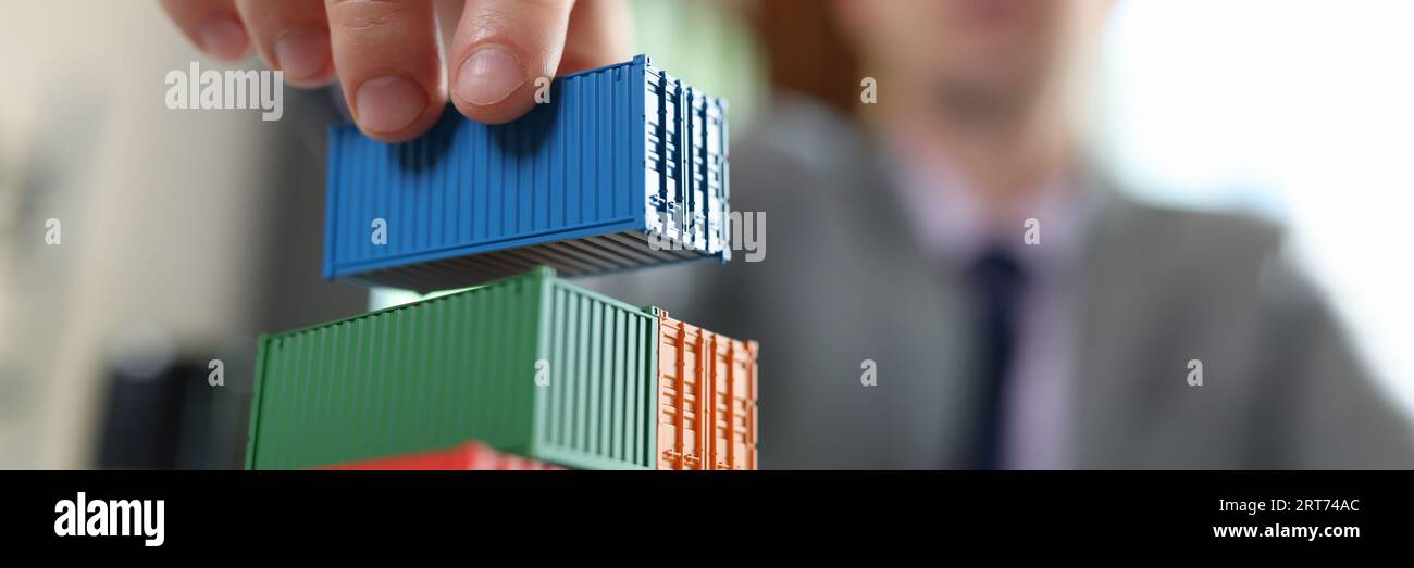 Business man arranging stack of cargo containers on his office desk ...