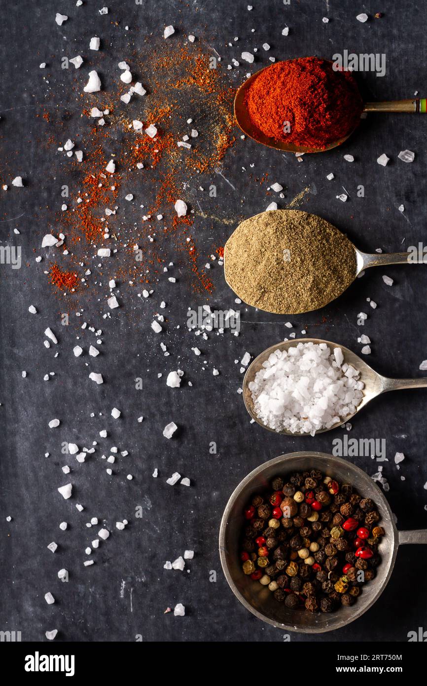 Old spoons with peppercorn, ground pepper, salt and red paprika powder ...