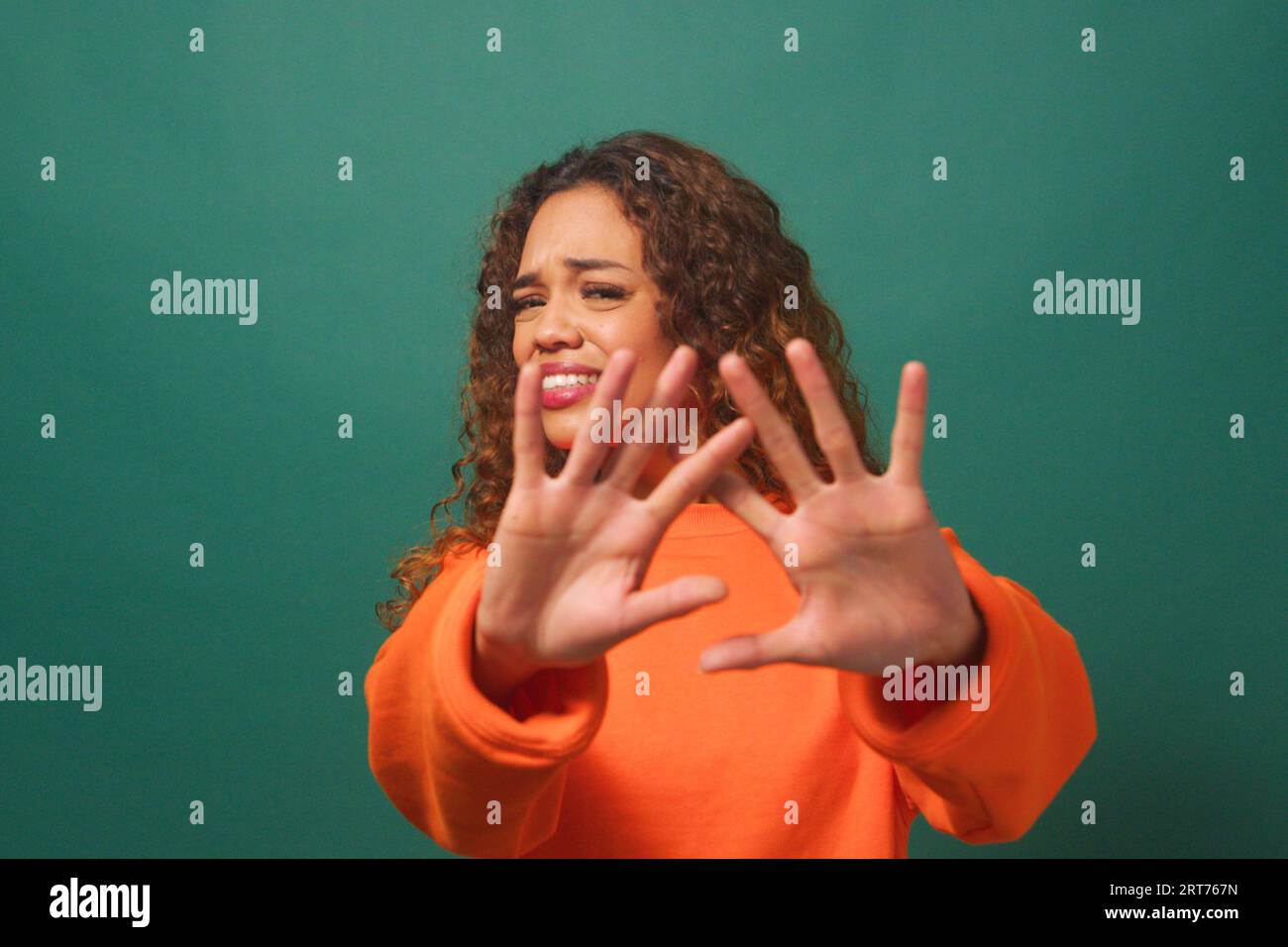 Young multi-ethnic woman holds up hands, hiding can't look, scared ...