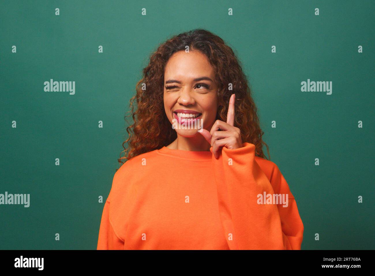 Beautiful young biracial woman wiggles and points one finger up, green ...