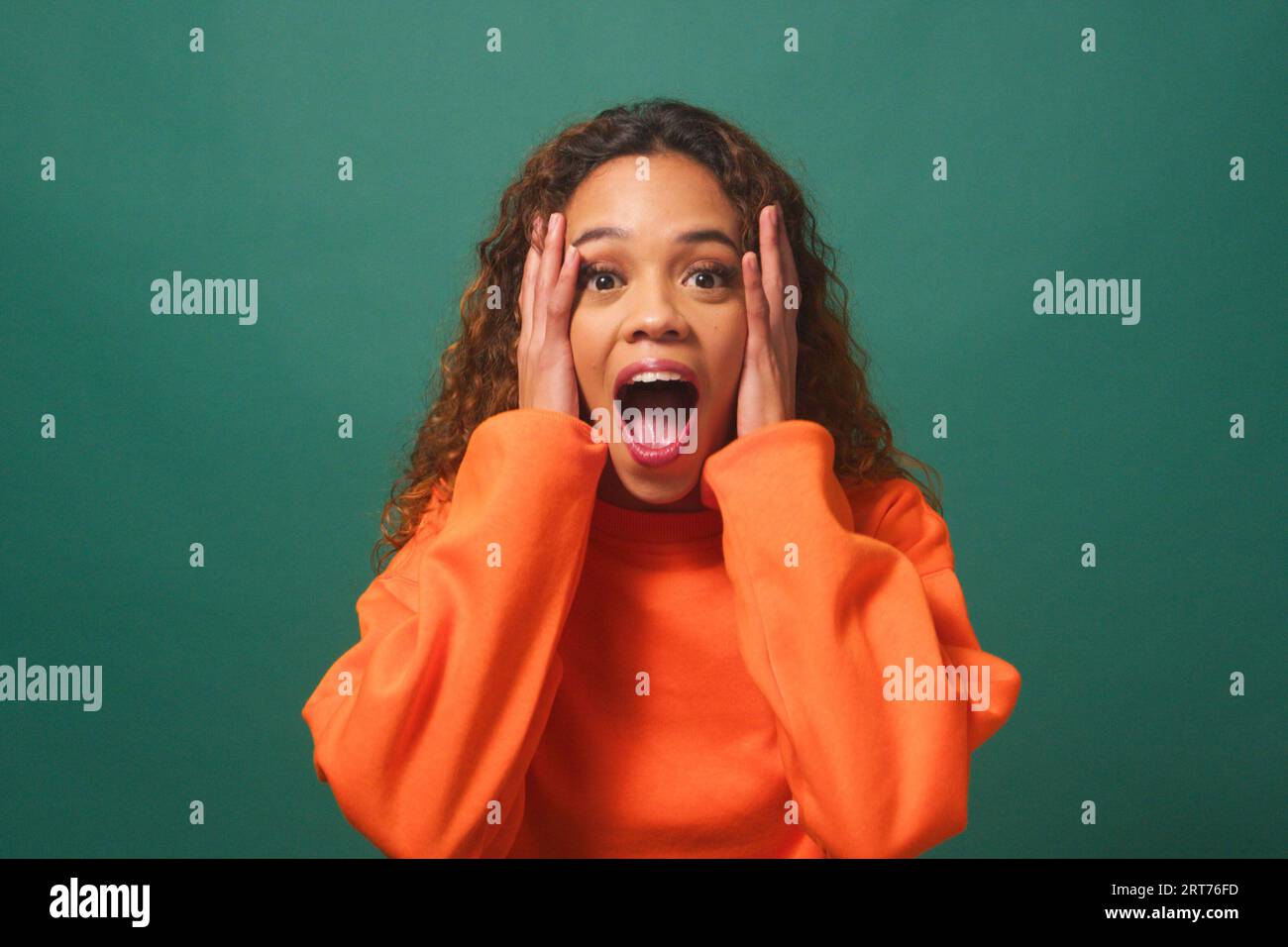 Happy shocked and surprised multi-ethnic woman, green studio background ...