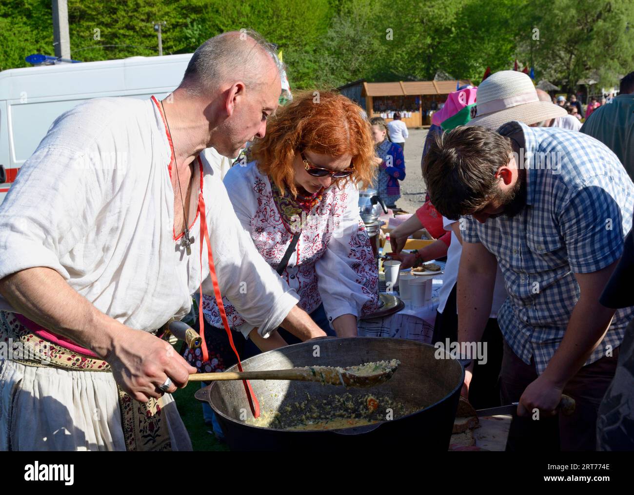 Man in Ukrainian national shirt feeding people of Cossack kasha ...