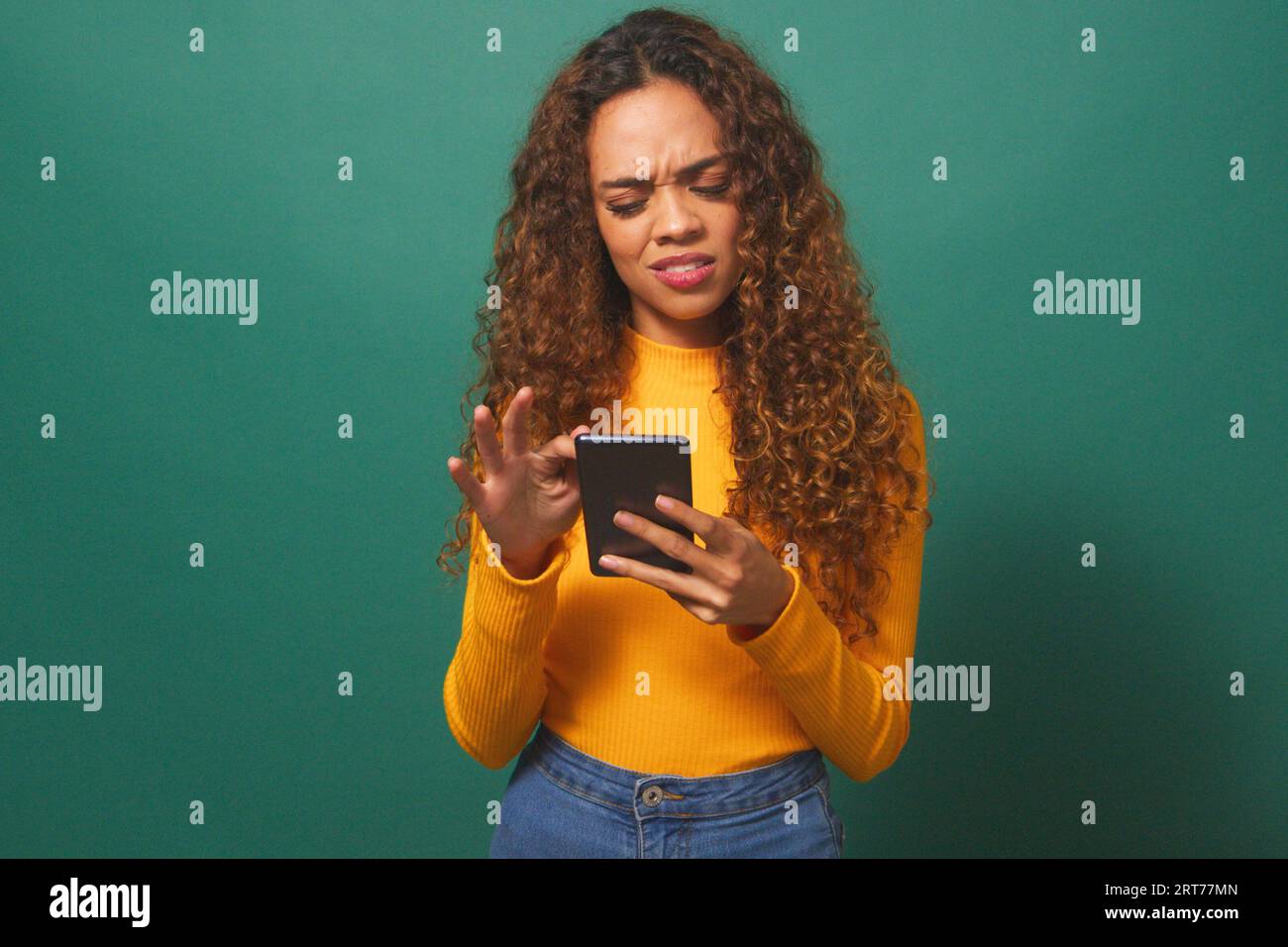 Young woman reads text message, disappointed confused, green studio ...