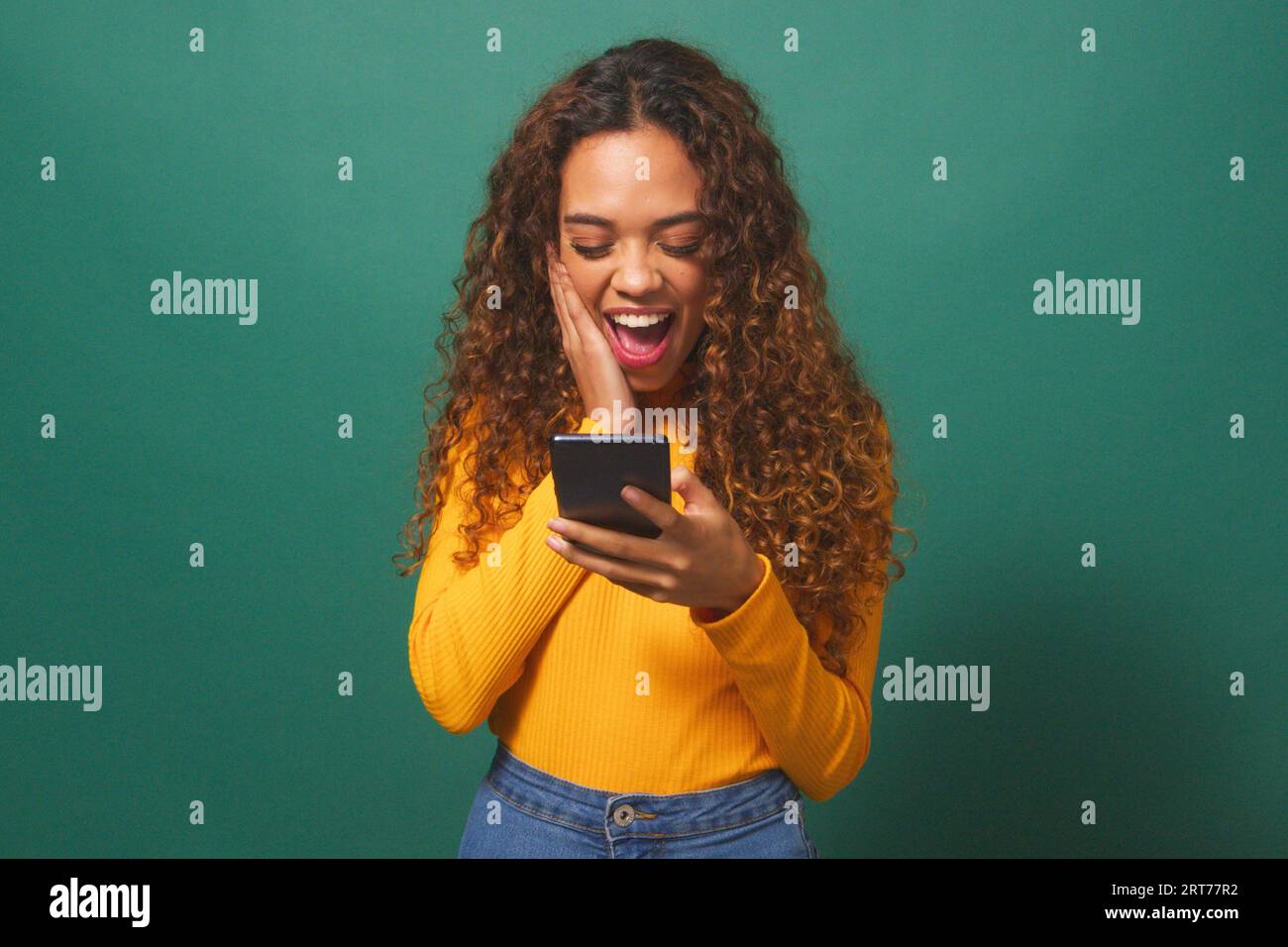 Young biracial woman reads text message shocked excited, green studio ...