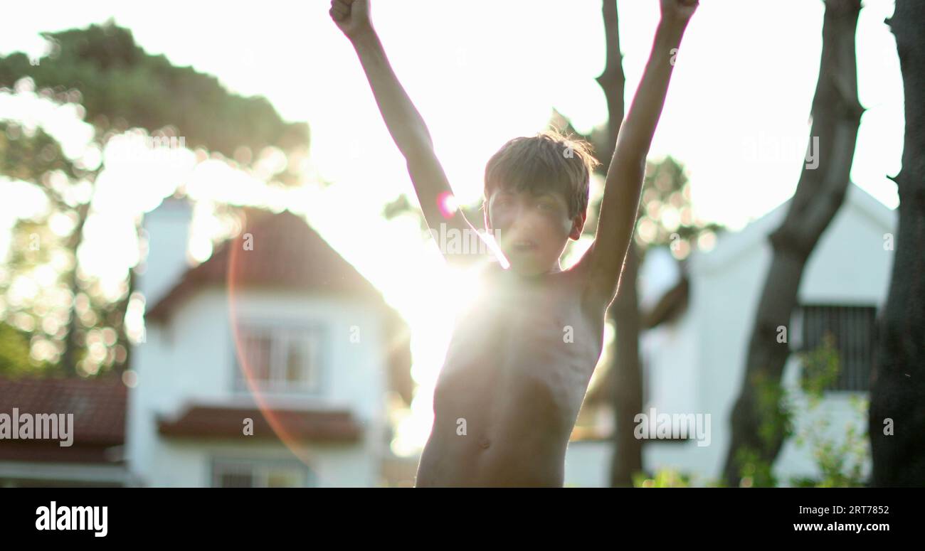 Boy raising arms in the sky clenching fists in victory and celebration ...
