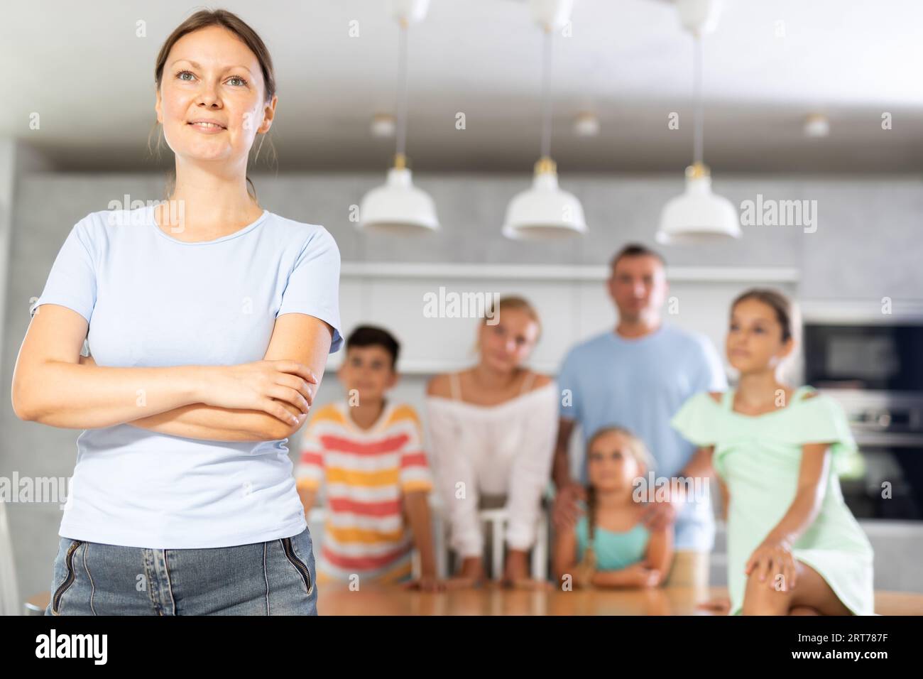 Smiling mum poses in cozy kitchen, large family with four children and ...