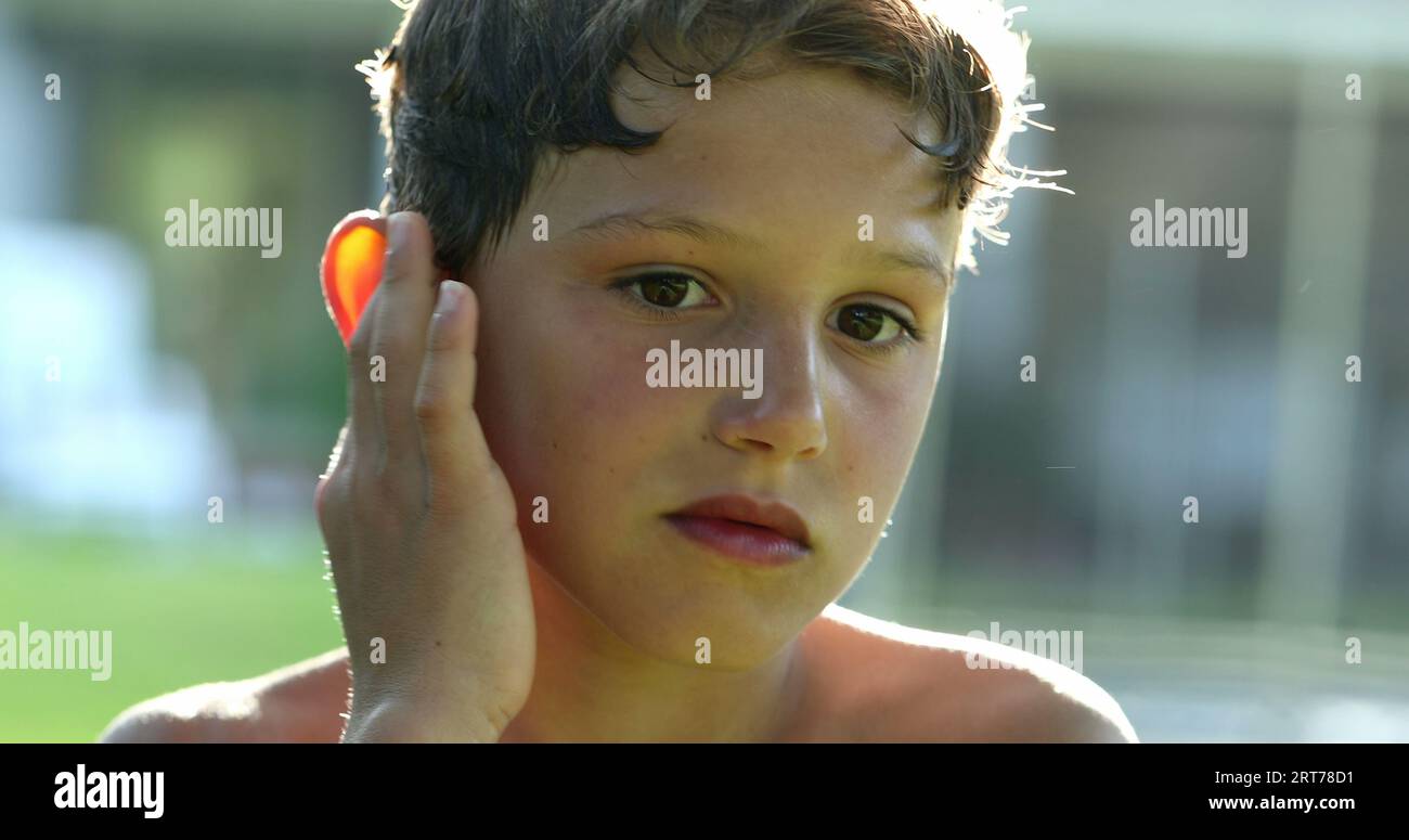 Boy scratching ear casually outside. Portrait of kid scratches body ...
