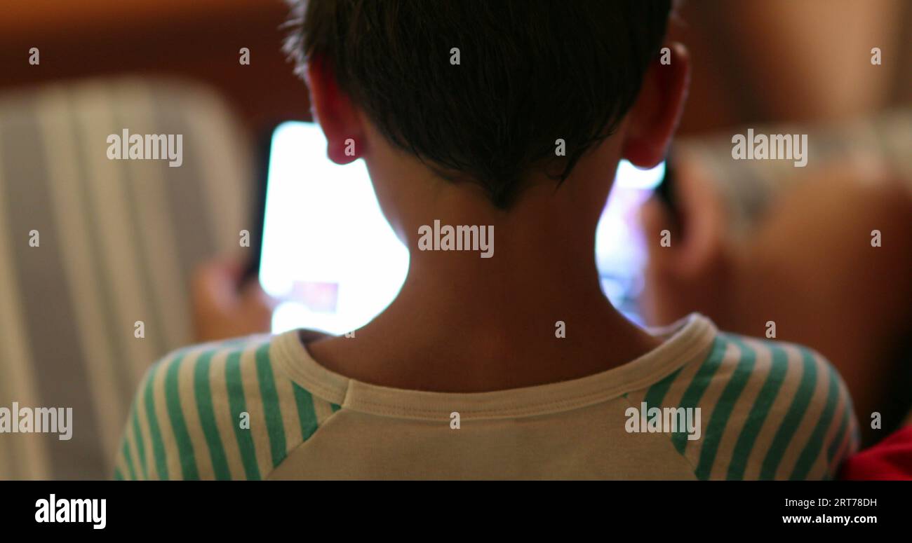 Boy staring at screen at night. back of Child watching content online ...