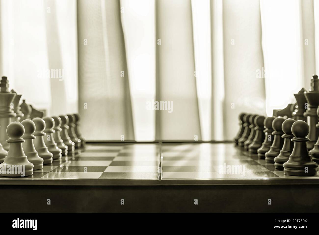 Chessboard next to the wide window with figures ready to play. Golden ...