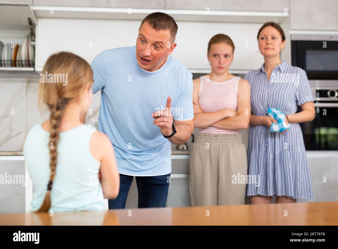 Preteen girl listening to disapproving words of father, mother and ...