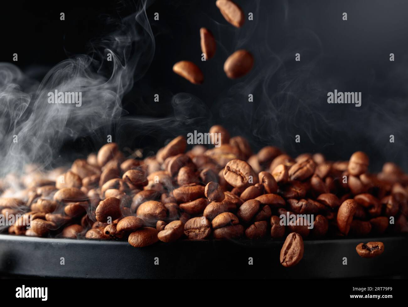 Steaming coffee beans in movement on a black background Stock Photo - Alamy