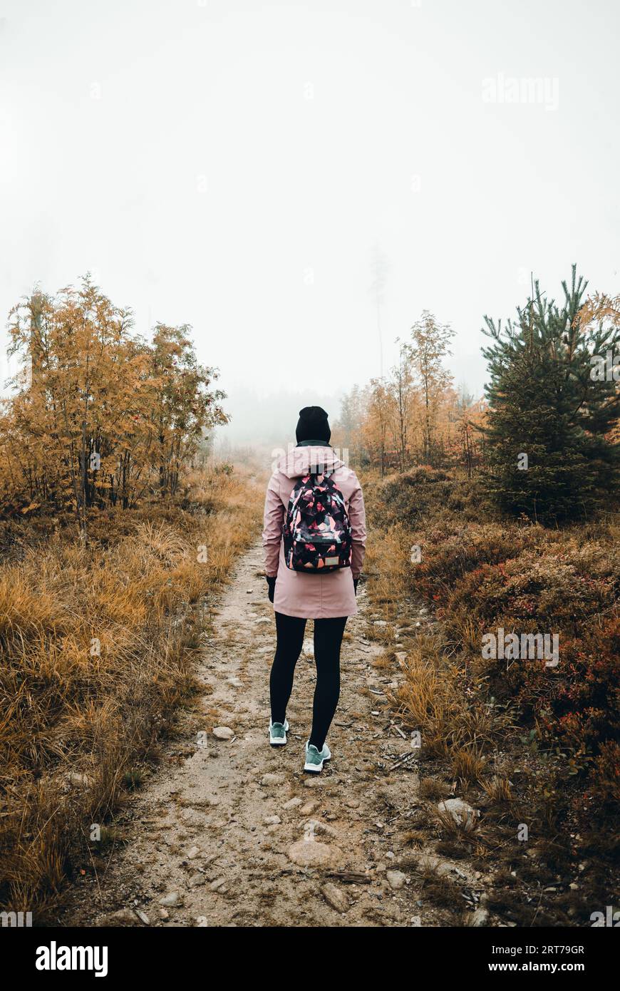 Portrait of young tourist woman with backpack in colorful autumn misty ...